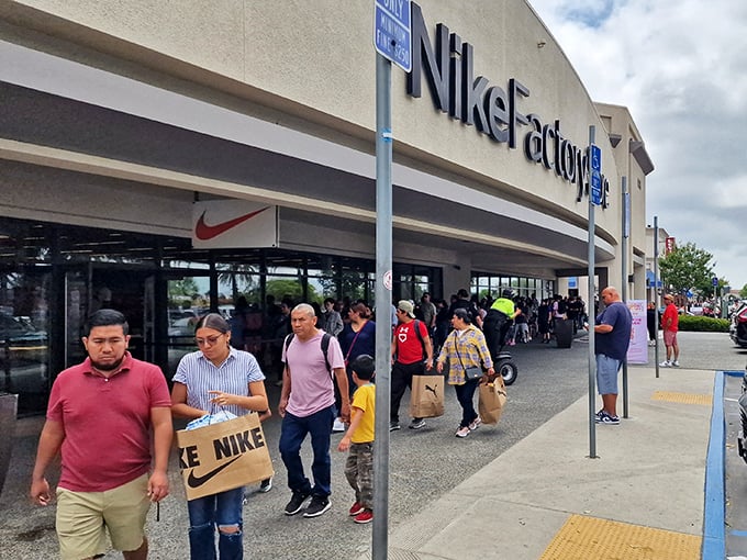 Victorious shoppers emerging from Nike Factory Store, bags in hand, with that unmistakable "scored a deal" glow.