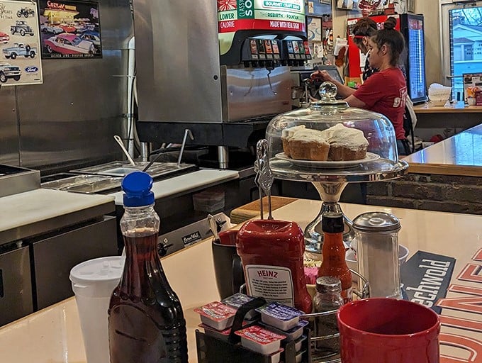 The condiment caddy – a miniature United Nations of flavor enhancers where Heinz ketchup plays ambassador to maple syrup and hot sauce diplomats.