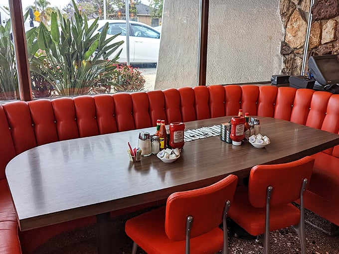 These red booths don't just seat you—they embrace you in vinyl comfort while condiments stand at attention, ready for duty.