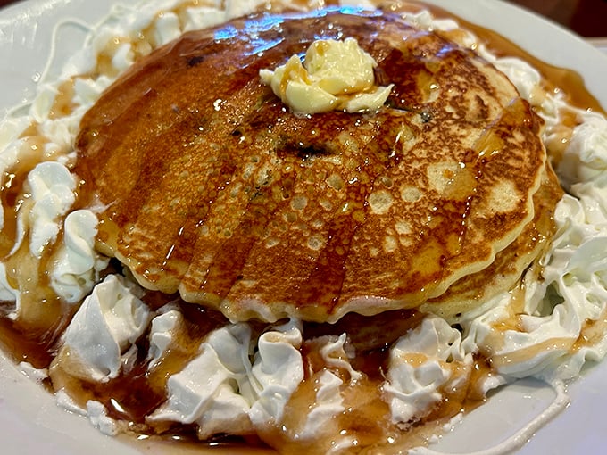 These golden pancakes surrounded by whipped cream aren't breakfast – they're dessert with permission to eat it before noon.