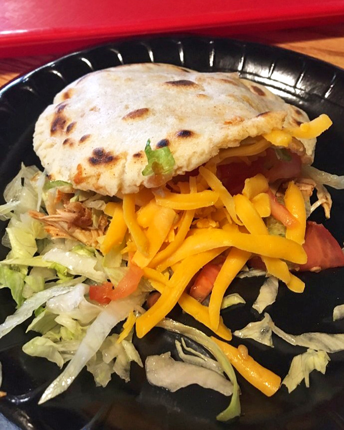 This gordita doesn't just sit on the plate – it commands attention with its golden exterior and colorful toppings. Handheld happiness at its finest.
