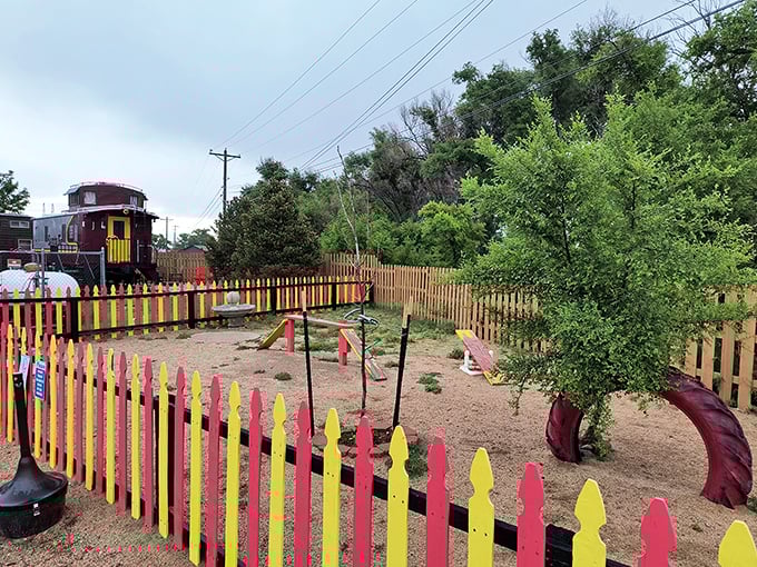 This colorful playground beside a vintage caboose reminds us that sometimes the simplest joys—like slides and imagination—are the ones we remember forever.