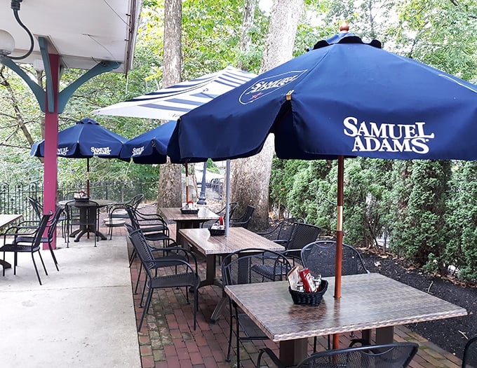 The outdoor patio, shaded by blue umbrellas, offers a peaceful retreat where summer breezes complement every bite of your meal.