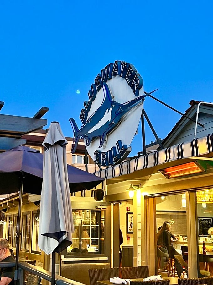 As evening falls, the Bluewater Grill sign glows like a beacon for seafood lovers. The perfect California night begins with that iconic marlin silhouette.