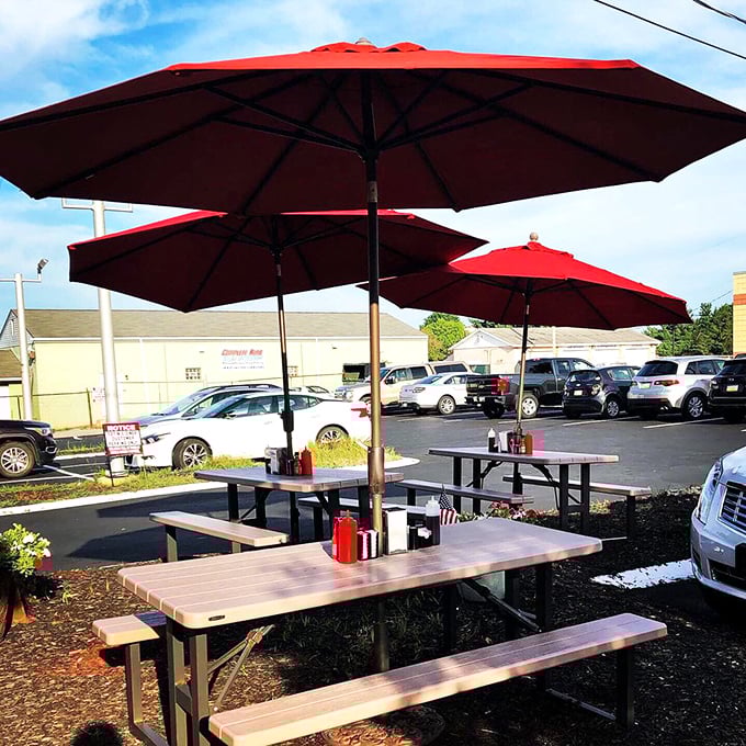Red umbrellas standing guard over outdoor tables—because sometimes pancakes taste even better with a side of fresh air.