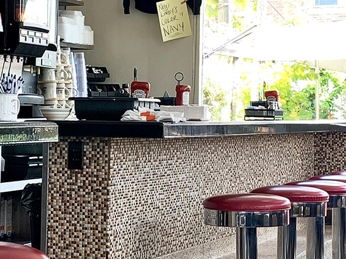 The mosaic-tiled counter where coffee cups are constantly refilled and local gossip flows as freely as the cream—the true heart of any great American diner.