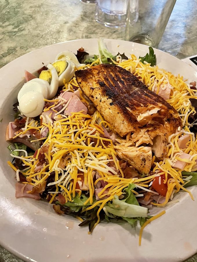 This isn't just a salad—it's a celebration of textures and flavors topped with perfectly grilled fish and enough cheese to make it worthwhile.