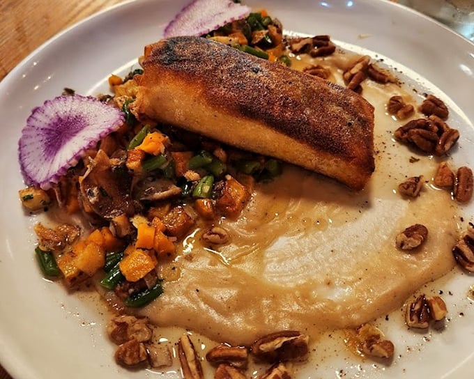 Salmon Wellington—where fish meets puff pastry in a marriage blessed by the culinary gods, surrounded by seasonal vegetables and pecan confetti.