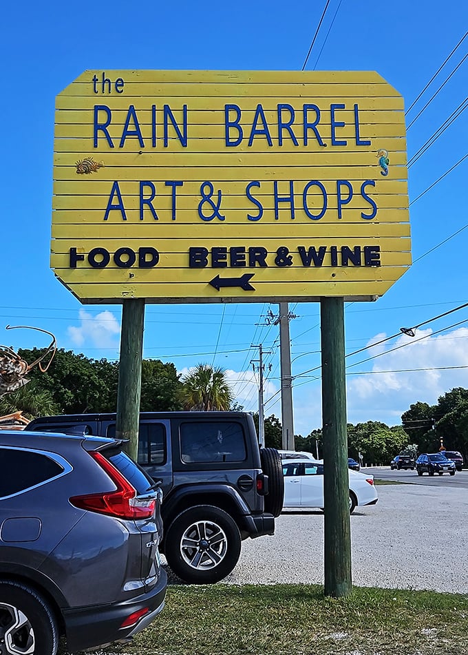 The yellow roadside sign makes a simple but important promise—art, shopping, and refreshments await just beyond the palm trees.