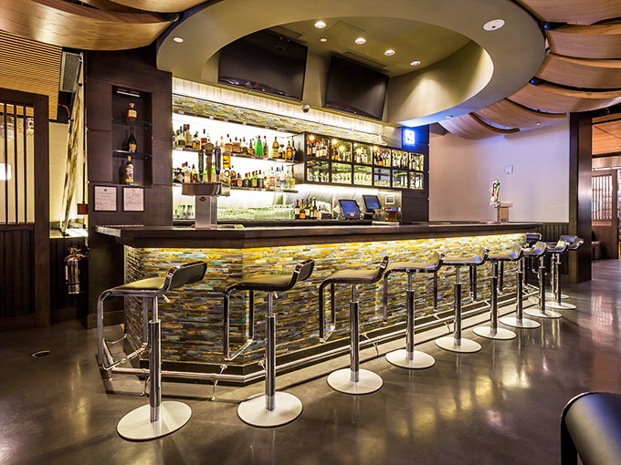 The bar isn't just serving drinks—it's showcasing liquid art beneath a ceiling that flows like a wooden river above.