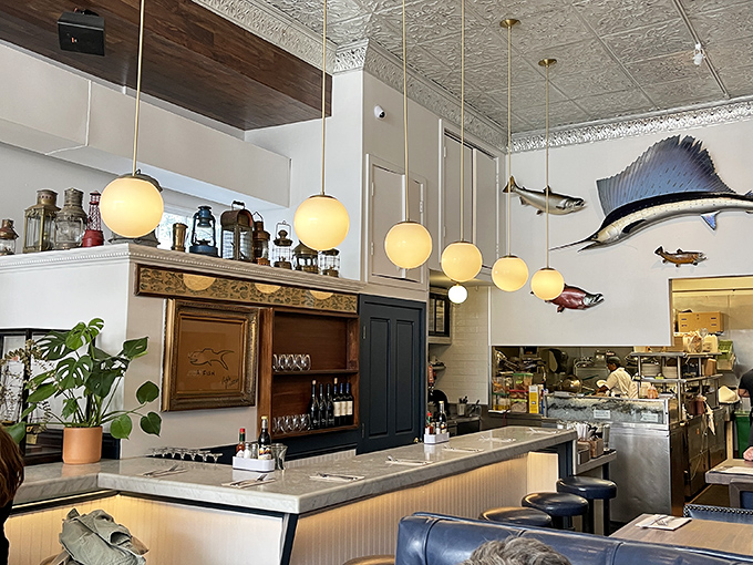 The bar area where maritime meets mixology, with pendant lights glowing like jellyfish and fish mounts watching over your dining decisions.