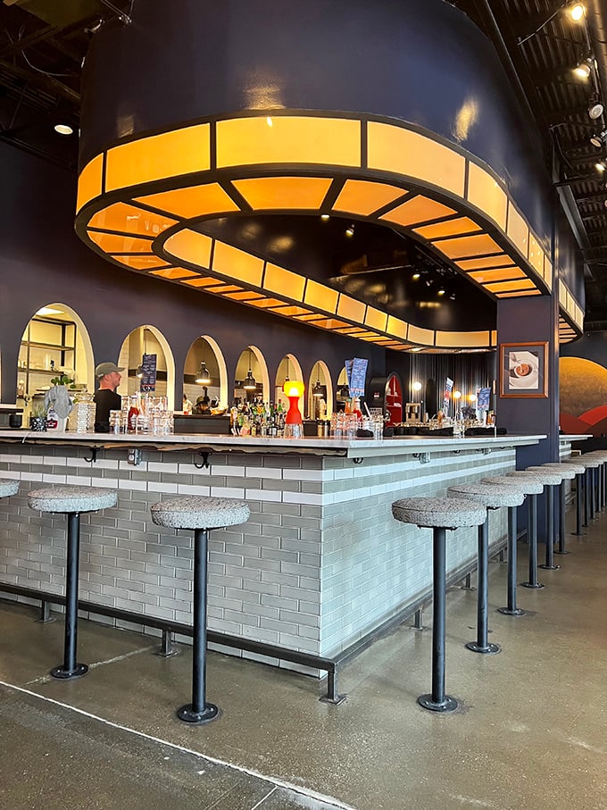 The bar area, with its illuminated circular fixture and sleek design, feels like the bridge of a stylish spaceship where the mission is serving excellent cocktails.
