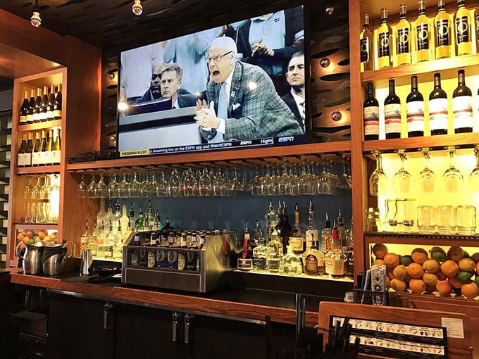 The well-stocked bar promises liquid accompaniments for every palate—from amber whiskeys to crisp wines, all backlit for maximum temptation.