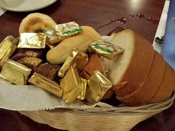 The bread basket—where butter packets nestle among rolls like golden treasure, because every great meal begins with good bread and anticipation.