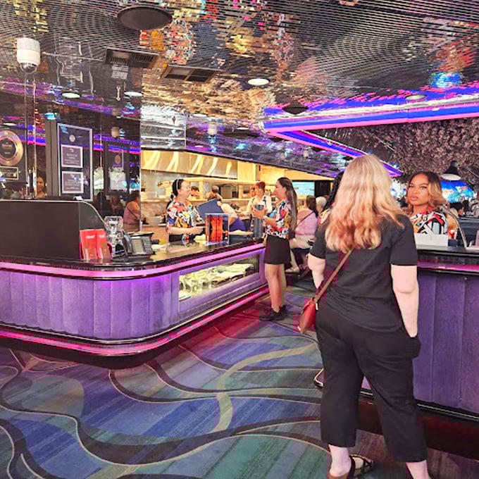 The heart of Peppermill's operation – where servers in tropical prints navigate the neon-lit interior like colorful fish in an aquarium of retro cool.