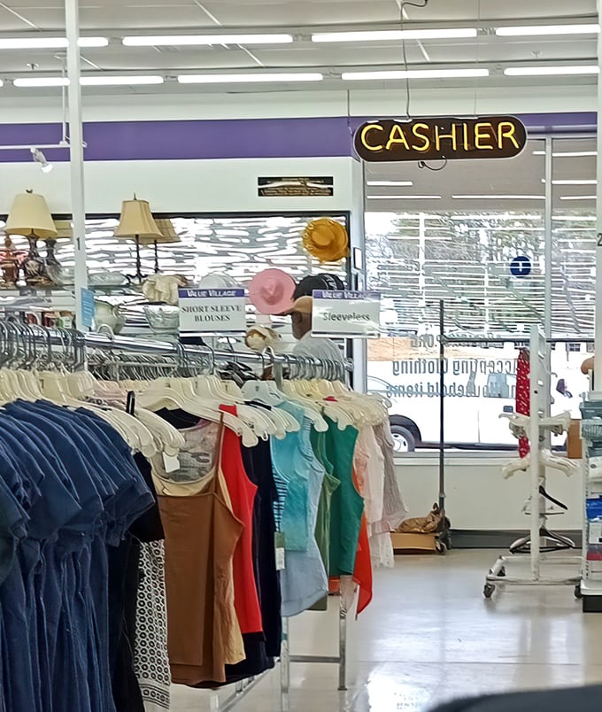 The neon "CASHIER" sign glows above clothing racks – the final checkpoint before your newfound treasures officially become yours.