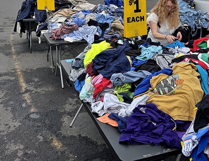 The dollar clothing table—where dedicated diggers plunge elbow-deep into fabric mountains, hunting for that hidden designer gem.