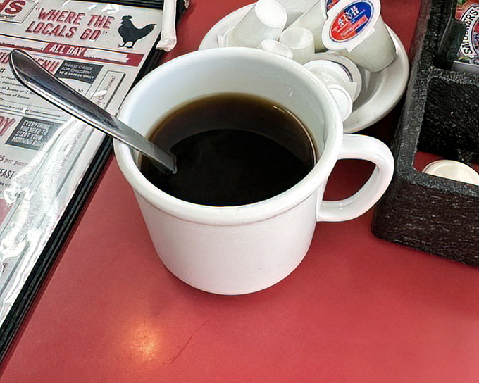 A simple cup of coffee on a red tabletop—the unsung hero of every great diner experience and the perfect companion to Ruth's breakfast masterpieces.