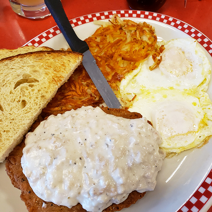 Country fried steak smothered in peppery gravy with sunny-side up eggs – a breakfast so hearty it could fuel a day of chopping wood.