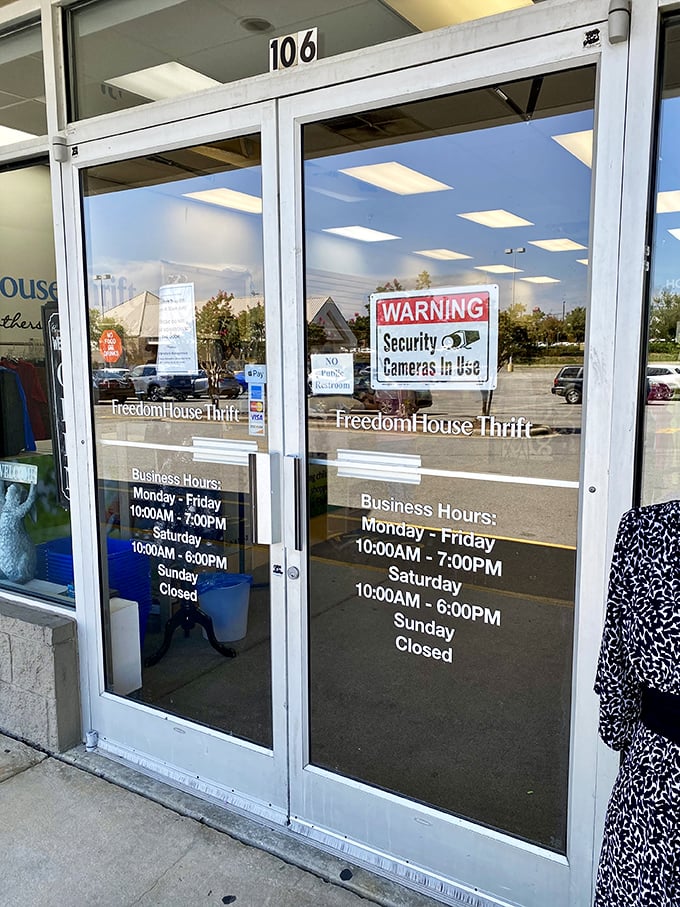 Business hours clearly posted for eager treasure hunters. The glass doors reflect both the parking lot and your thrifting possibilities.