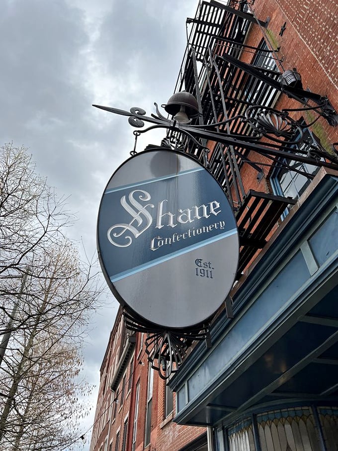 The hanging oval sign swings above Old City like a pocket watch hypnotizing passersby—"Come in," it whispers, "calories consumed beneath historic signs don't count." 