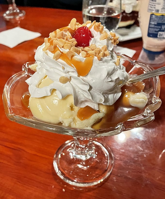 This isn't just dessert—it's architecture with whipped cream, a caramel waterfall cascading over vanilla ice cream with the cherry on top serving as the perfect exclamation point.