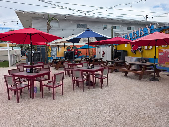 Outdoor seating that invites you to linger – red umbrellas providing shade while you contemplate ordering just one more round of those grouper bites.