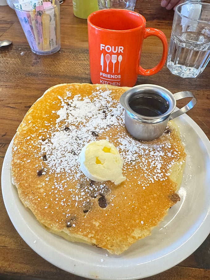This pancake isn't just big—it's the solar system of breakfast plates, with butter melting like a supernova and powdered sugar mimicking distant stars.