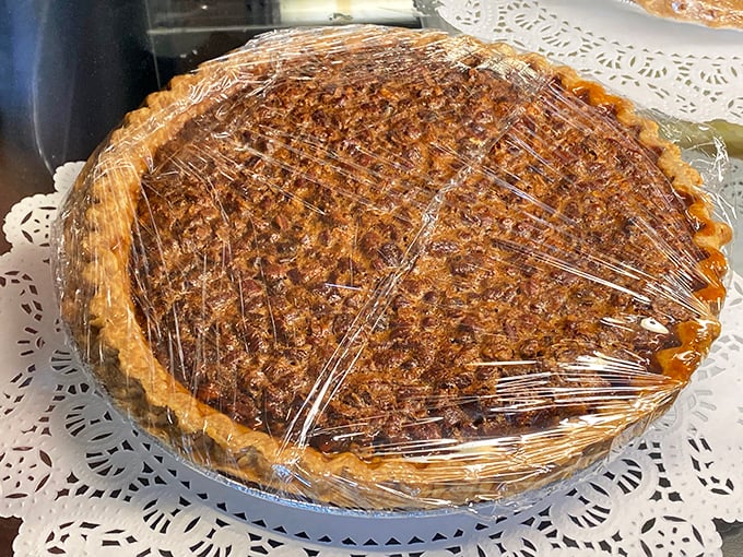 Pecan pie waiting patiently under wrap, its caramelized top glistening with promise – the kind of dessert that makes you consider ordering before your meal.