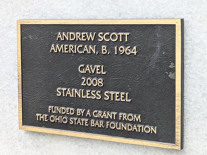 The artist's calling card. This plaque reveals the mastermind behind the monumental mallet—Andrew Scott created this stainless steel conversation piece in 2008, funded by legal eagles who clearly think big.