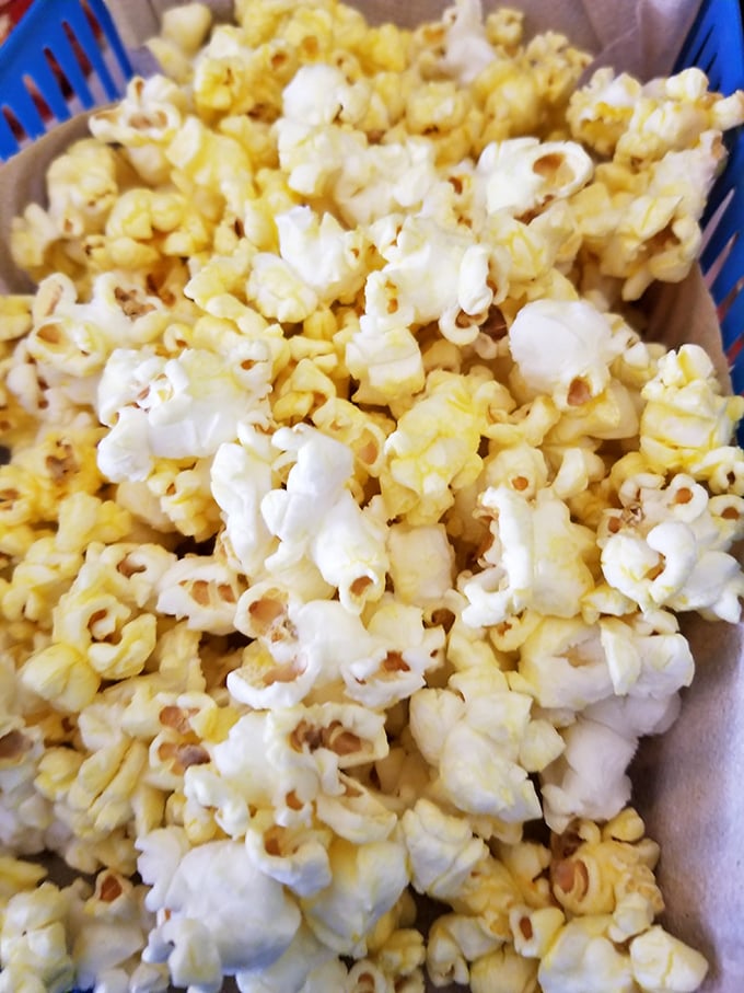 Buttery popcorn served in a blue basket – the unexpected appetizer that keeps your hands busy while decisions are made.