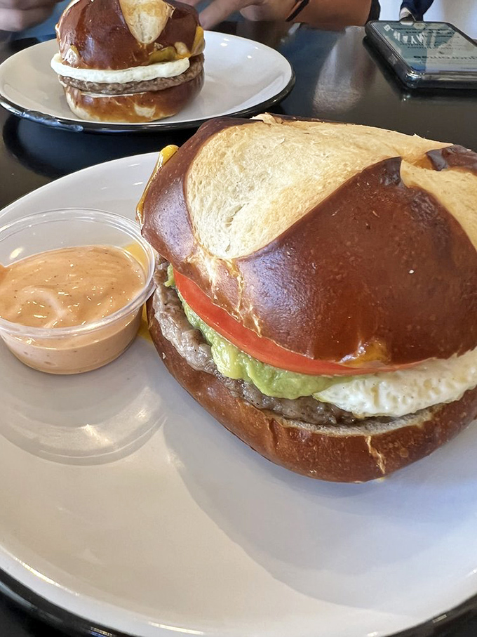 This isn't just a breakfast sandwich—it's morning salvation. The glossy pretzel bun cradles egg, cheese, and savory goodness with a side of spicy aioli.