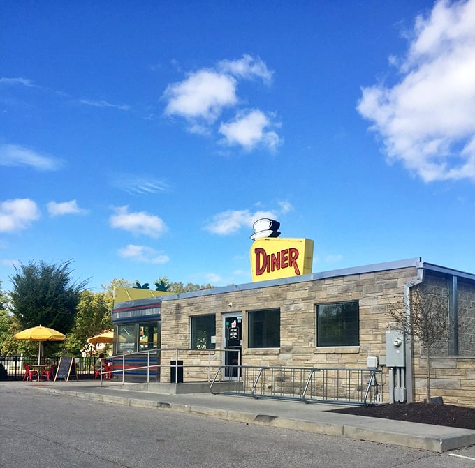 Morning sunshine highlighting the diner's classic profile—stone meets steel meets neon in an architectural love letter to America's roadside dining heritage.