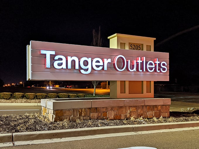 The glowing Tanger sign stands like a retail lighthouse, guiding bargain hunters safely to shore even after the sun goes down.