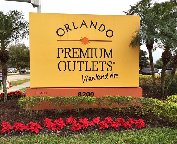 The cheerful entrance sign surrounded by poinsettias—your first clue that retail therapy of the highest order awaits just beyond.