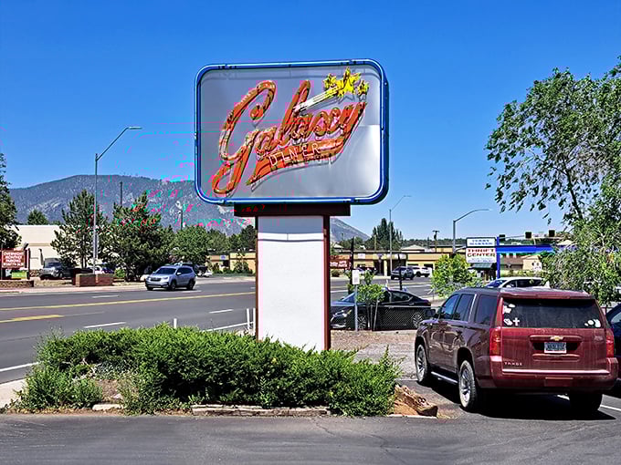 The sign stands sentinel against the mountain backdrop, like a mid-century modern lighthouse guiding hungry travelers to safe harbor. Those peaks aren't just scenery—they're the audience.