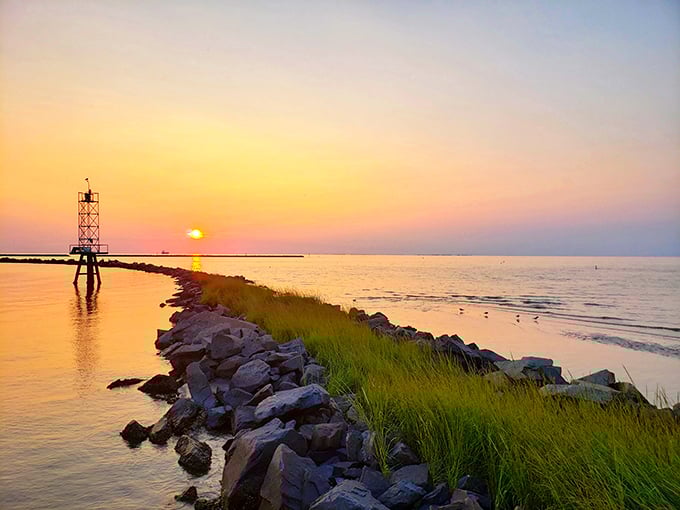 The sun performs its nightly magic show over the breakwater, painting the sky in impossible colors that no Instagram filter could ever truly capture.