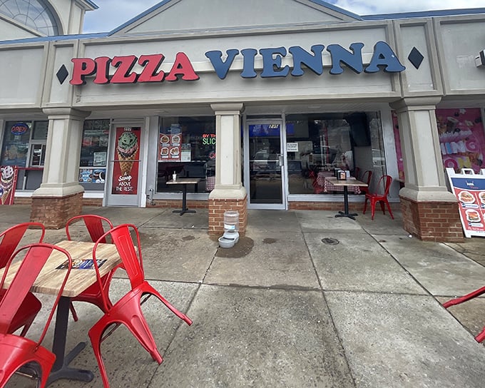 Pizza Vienna's storefront welcomes you with those cherry-red chairs – like little flags signaling "great pizza ahead!"