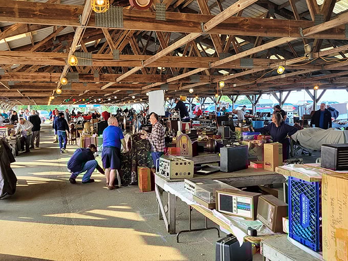 The thrill of the hunt in action. Shoppers scan tables of electronics and collectibles under rustic rafters at this Kutztown institution.