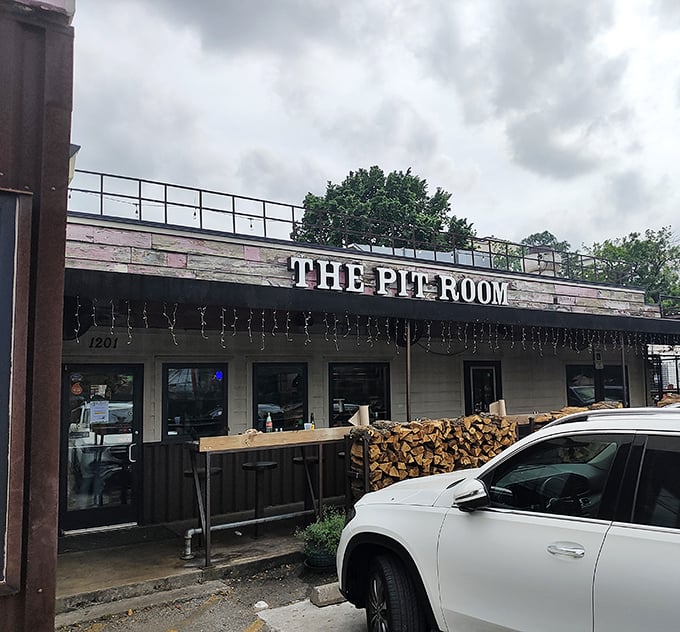 Rustic charm meets serious BBQ at The Pit Room. That woodpile isn't decoration—it's a promise of good things smoking inside.