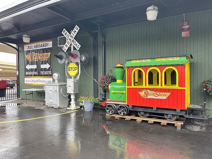 The boarding area's colorful mini-train welcomes visitors with a cheerful "All Aboard!" – like a Wes Anderson film set come to life.