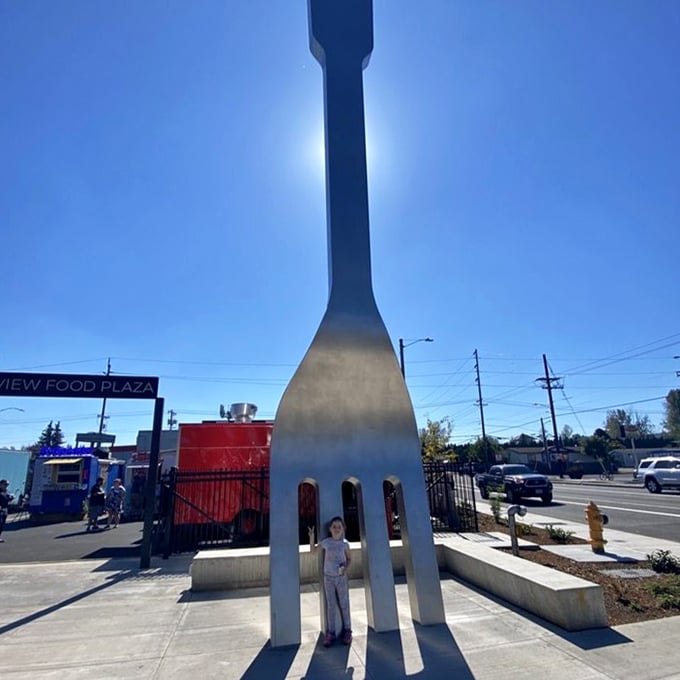 Against a perfect blue Oregon sky, the fork reaches skyward like a metallic monument to mealtime, dwarfing visitors who stand beneath it.