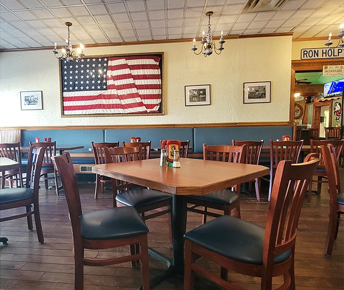 Classic Americana adorns the walls while wooden chairs and tables invite you to settle in. That vintage flag isn't just decoration—it's a promise of old-school quality.