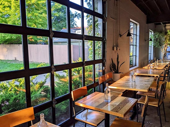 Sunlight streams through floor-to-ceiling windows, illuminating wooden tables that practically beg you to linger over coffee. Industrial-meets-cozy at its finest.