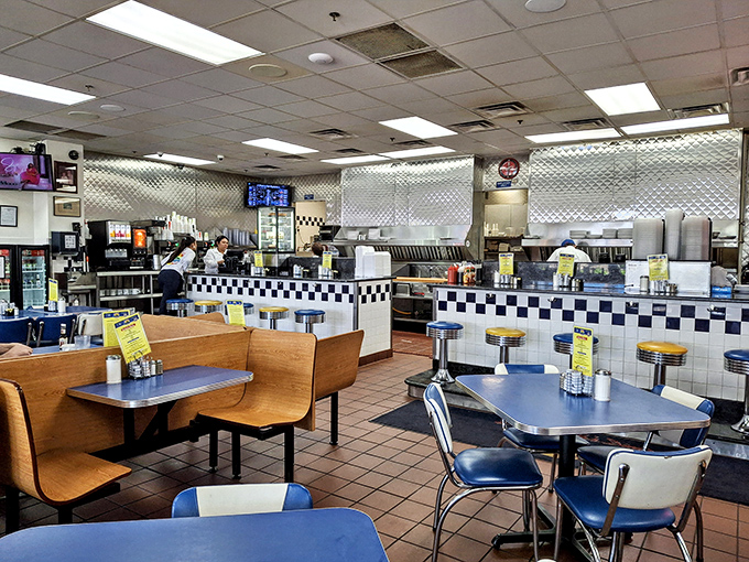 Classic diner geometry: blue tables, checkerboard counters, and the symphony of spatulas on griddles. This is where breakfast dreams come true, regardless of the hour.