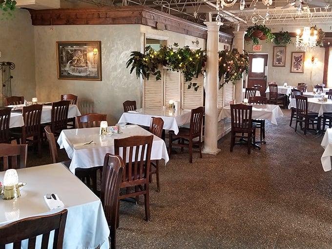 White tablecloths meet rustic wooden beams in this dining room where comfort meets elegance. The columns wrapped in greenery create intimate dining nooks.