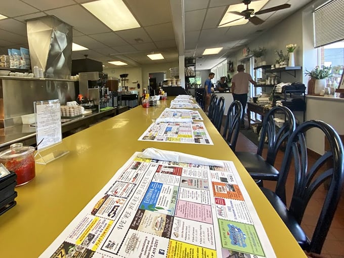 The iconic yellow counter stretches like a runway of culinary possibilities, each placemat a roadmap to comfort food paradise.