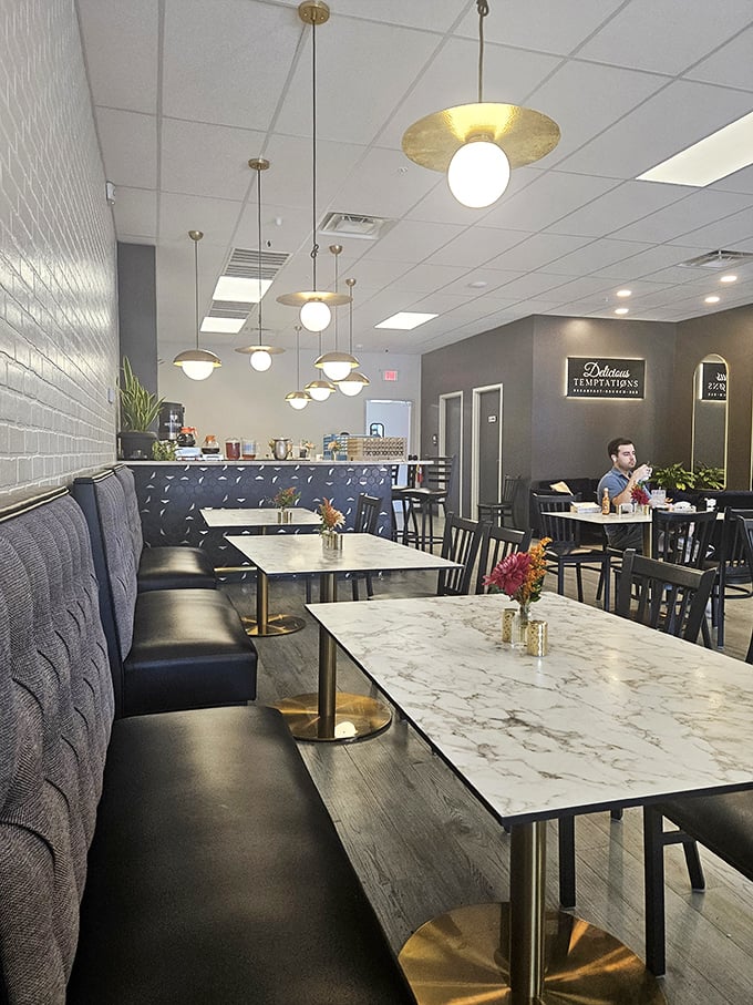 Modern elegance meets breakfast comfort inside, where pendant lights cast a golden glow over marble tables and cozy booths.