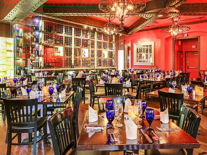 Rich reds and cobalt blue goblets create an atmosphere that whispers "special occasion" while the wine wall silently promises perfect pairings.