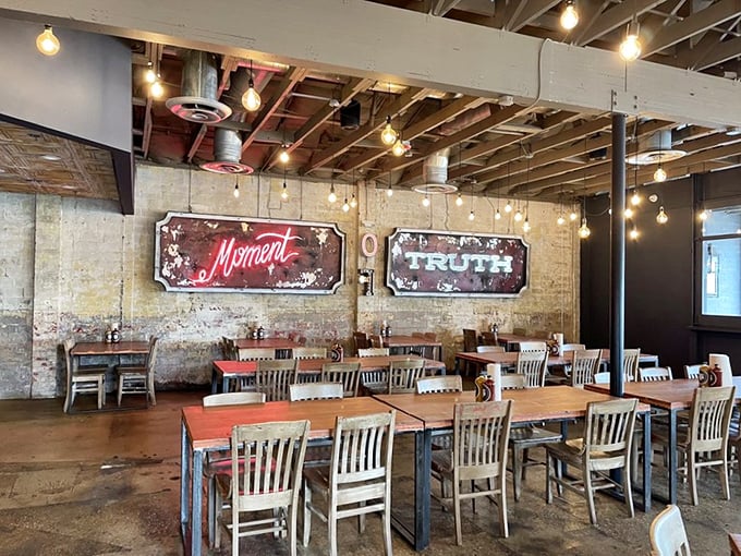 Edison bulbs illuminate exposed brick walls adorned with vintage-style "Moment" and "Truth" signs—a dining room that feels both timeless and Instagram-ready.